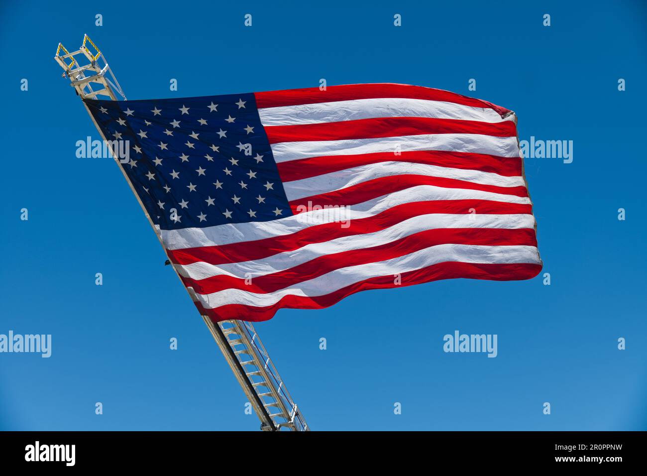 The US flag flies from a fire dept. aerial ladder at a motorcycle event ...