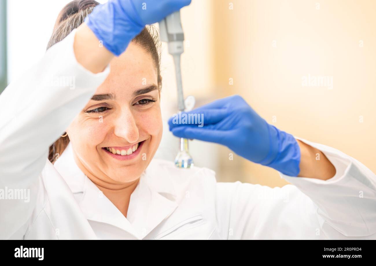 Scientist with dropper dripping liquid into a test tube in scientific ...