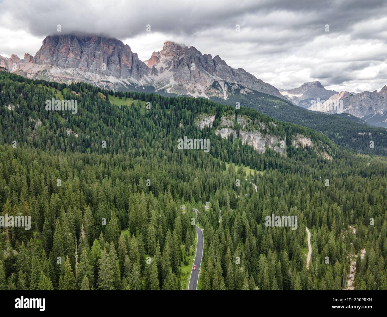 Aerial shot of a curvy road in a forest near the giau pass in the ...