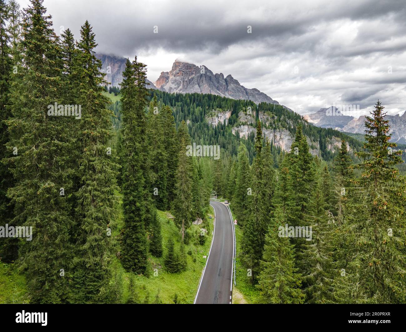 Aerial shot of a curvy road in a forest near the giau pass in the ...