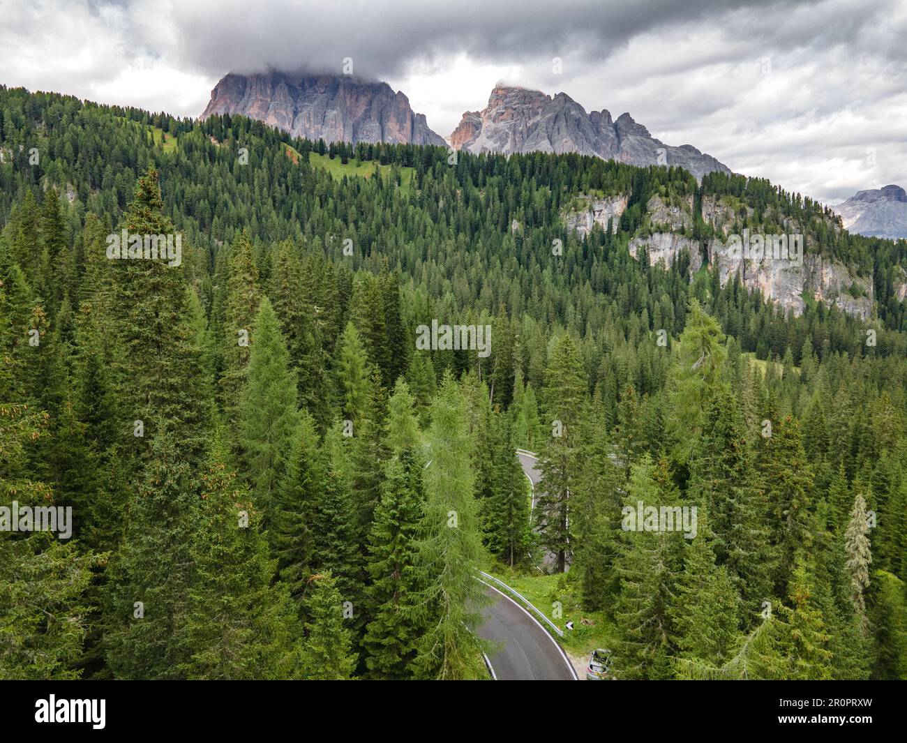 Aerial shot of a curvy road in a forest near the giau pass in the ...