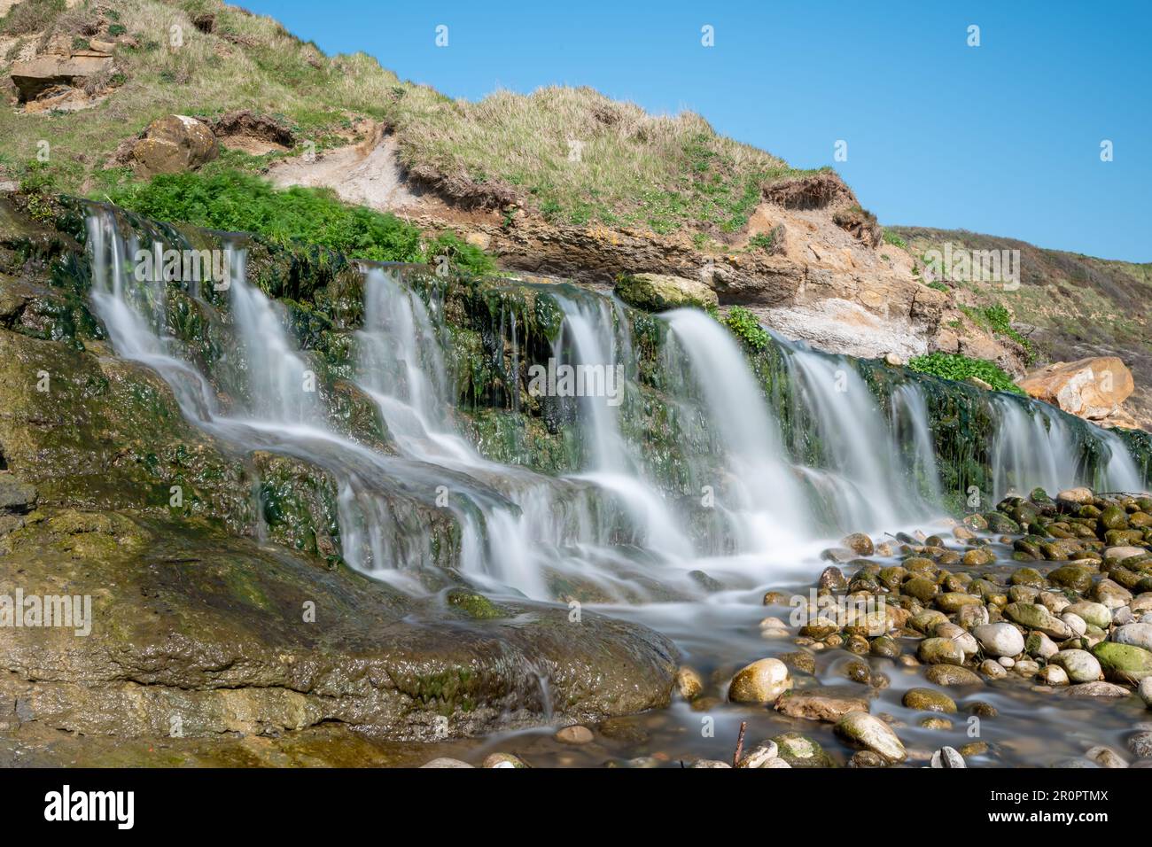 Long exposure of the waterfall flowing onto the beach at Osmington ...