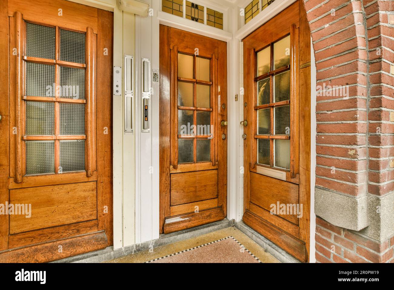 two wooden doors in front of a brick building with glass inserts on the ...