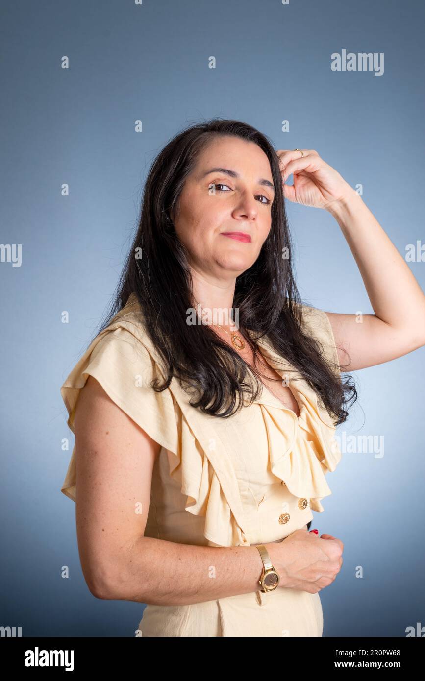 A young adult woman stands in front of a white background, with her ...