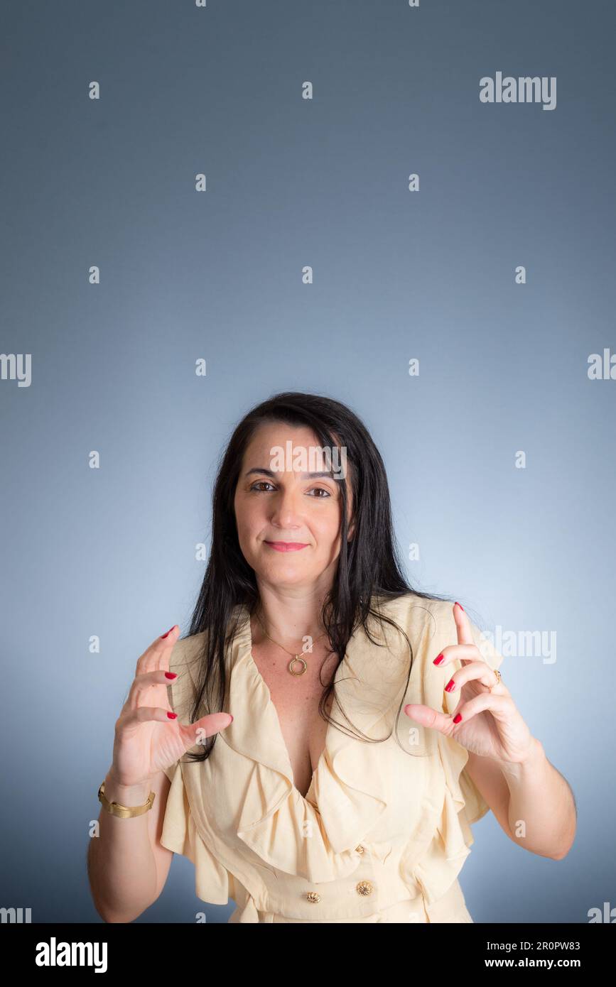 A female adult stands with her arms raised in a gesture of joy and ...