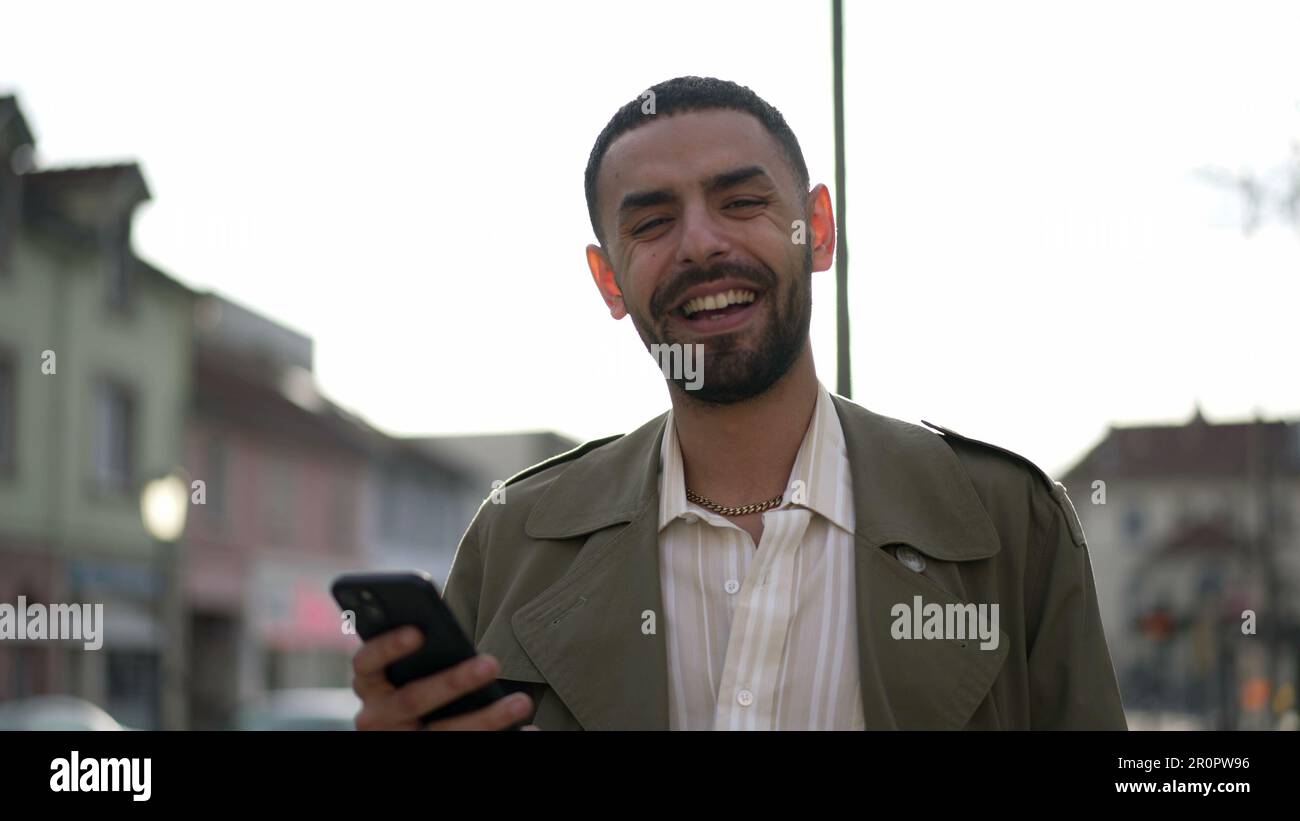 One happy Arab young man closeup face smiling while holding cellphone ...