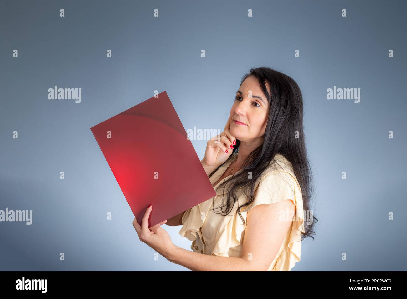 A young female standing on a blue background with her hands poised on a ...