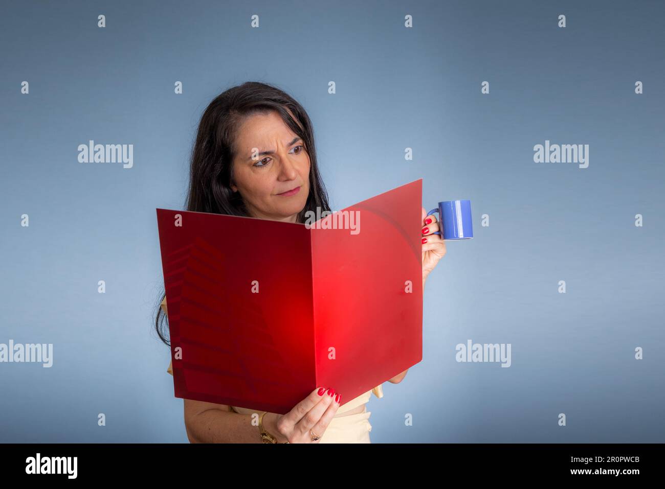 A determined female professional looks intently at a vibrant red folder ...