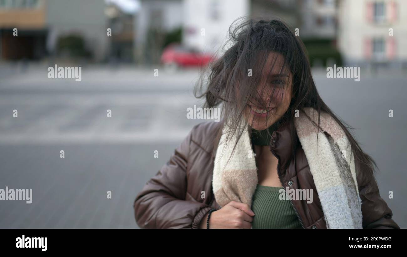 One happy carefree young woman running outside in urban street turning ...