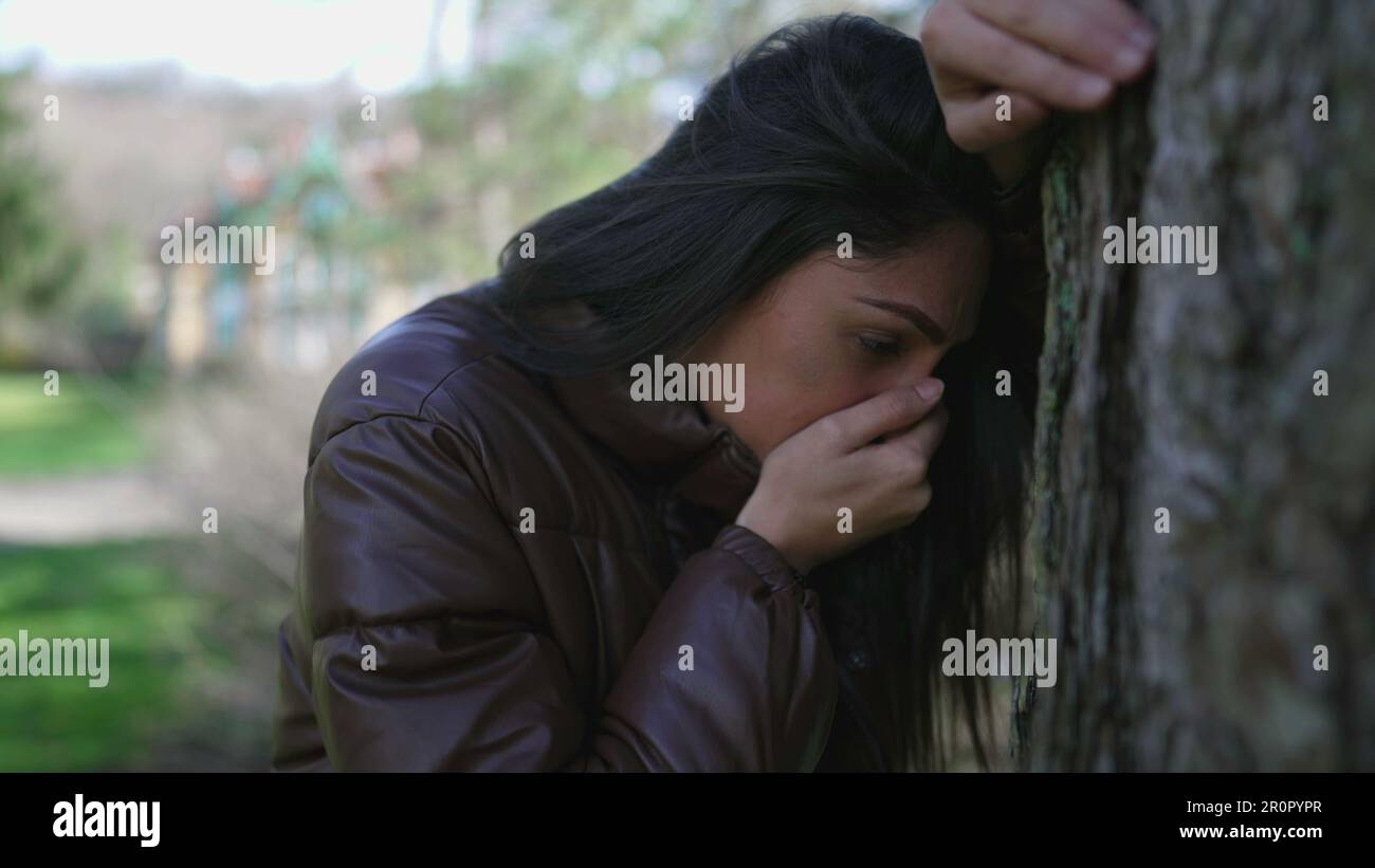 Suffering young woman leaning on tree outside feeling desperate. Adult ...