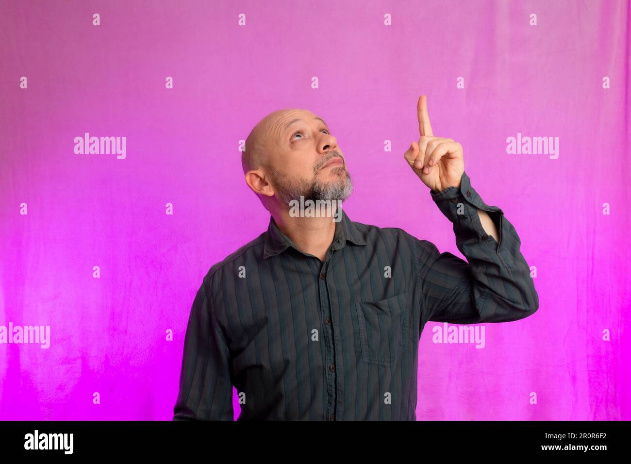 50 years old man, funny, pointing his finger up. Isolated on pink ...