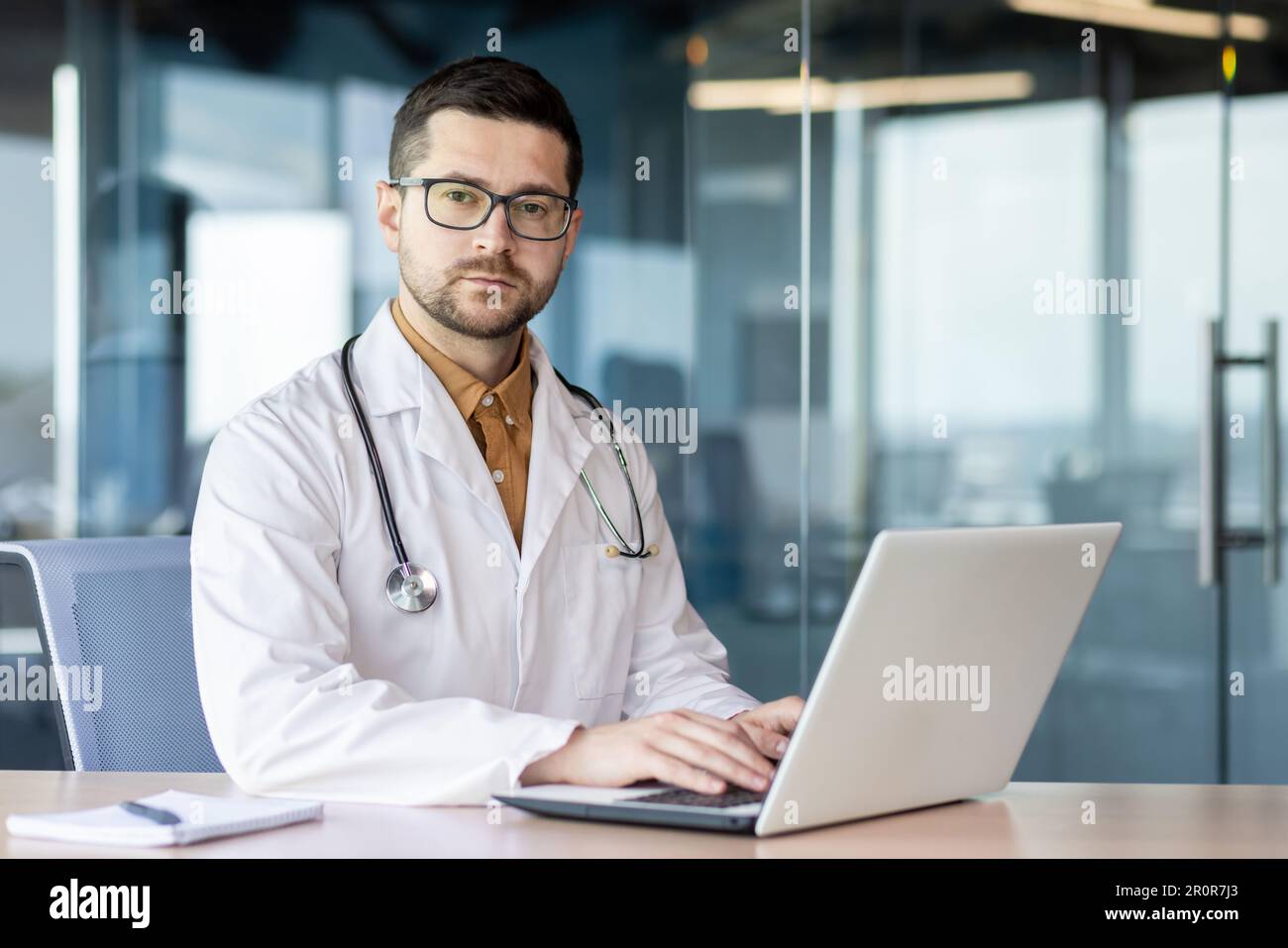 Portrait of a young serious doctor inside the office at the workplace ...