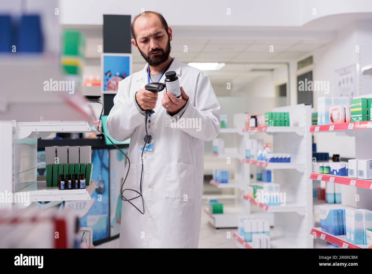 Caucasian pharmacist holding pills bottle scanning products bar code ...