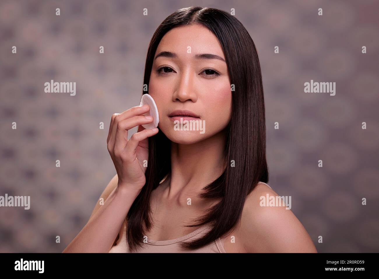 Asian woman using cotton pad to remove facial foundation cream ...