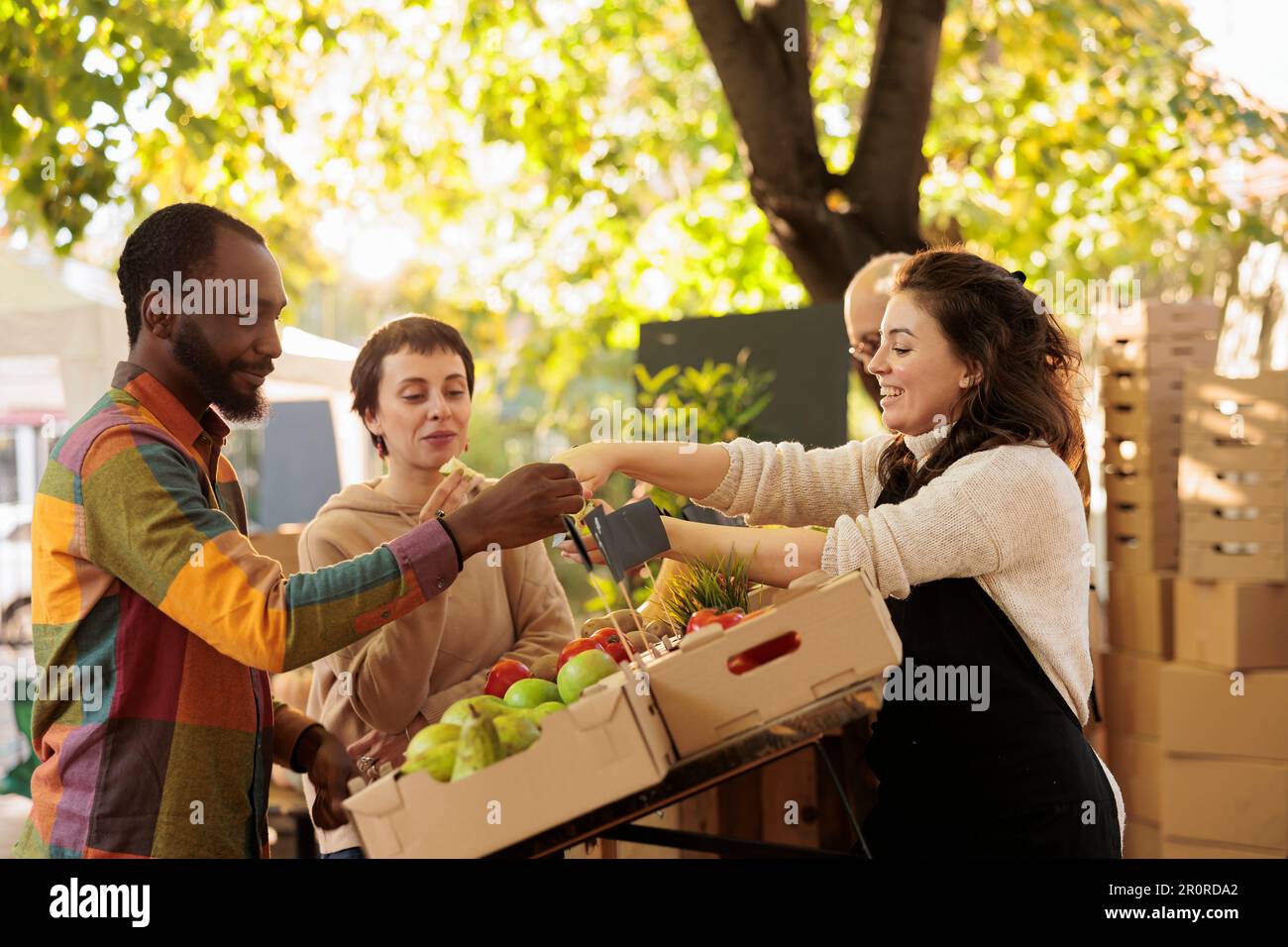 Vendor offering samples to customers while selling home-grown fruits ...