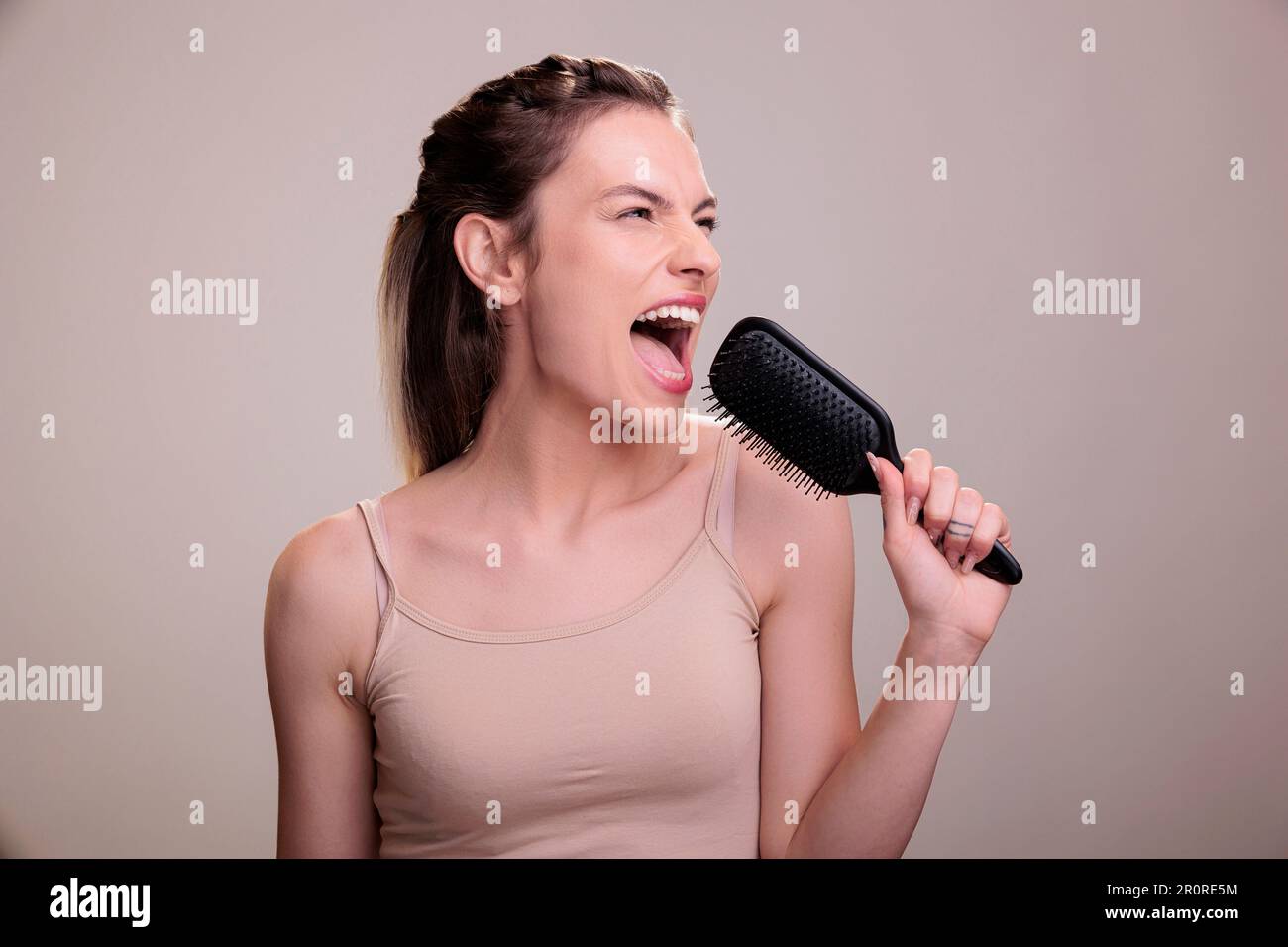 Beautiful woman singing loudly in hairbrush during hairstyle routine ...