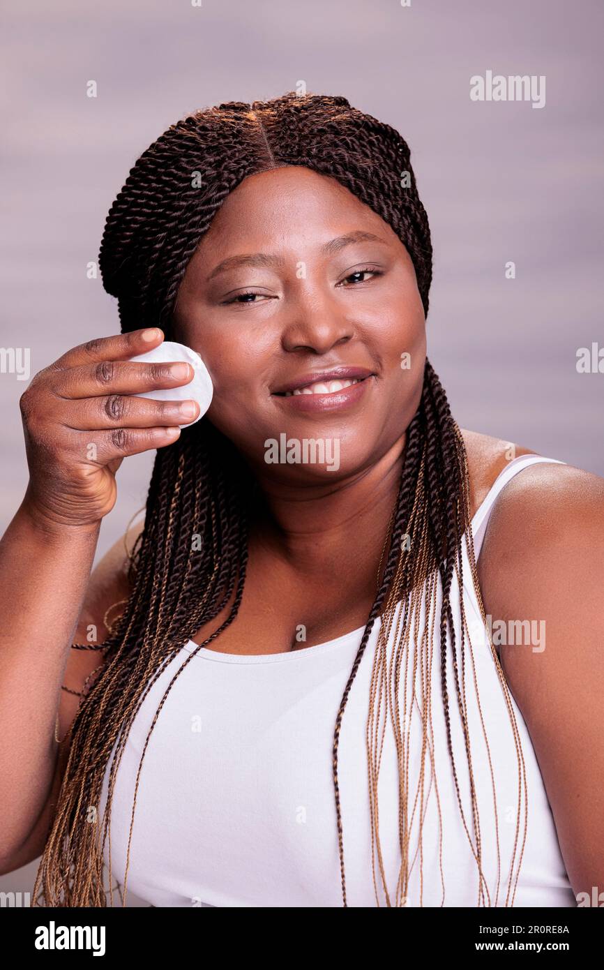 Plus size smiling model using cotton pad disk for facial makeup ...