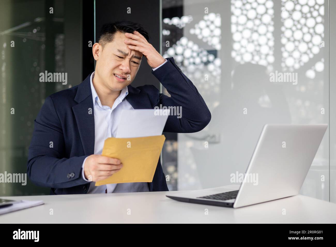 Serious and upset asian businessman reading letter with bad news ...