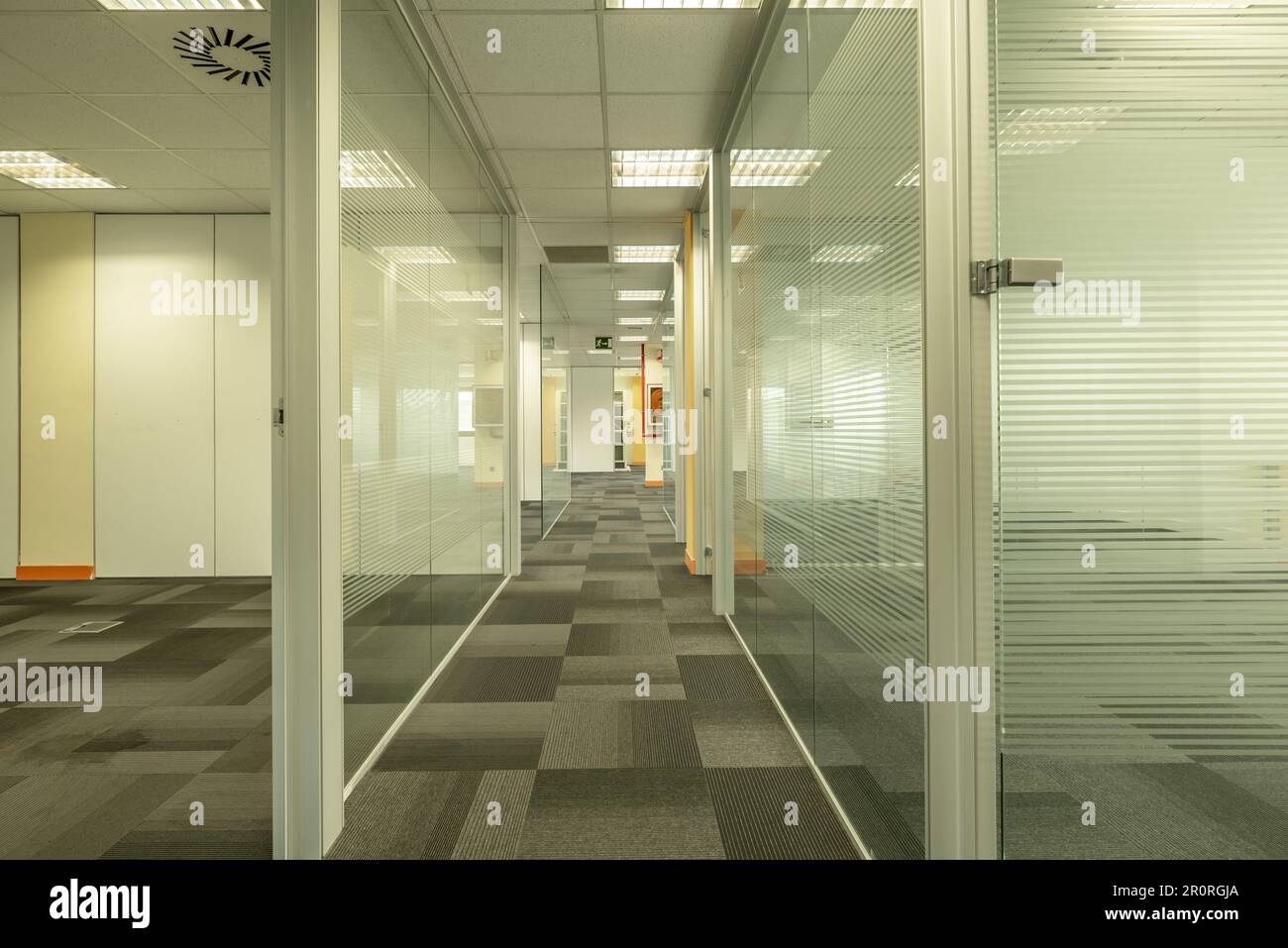 Empty offices with glass partitions and a long corridor between them ...