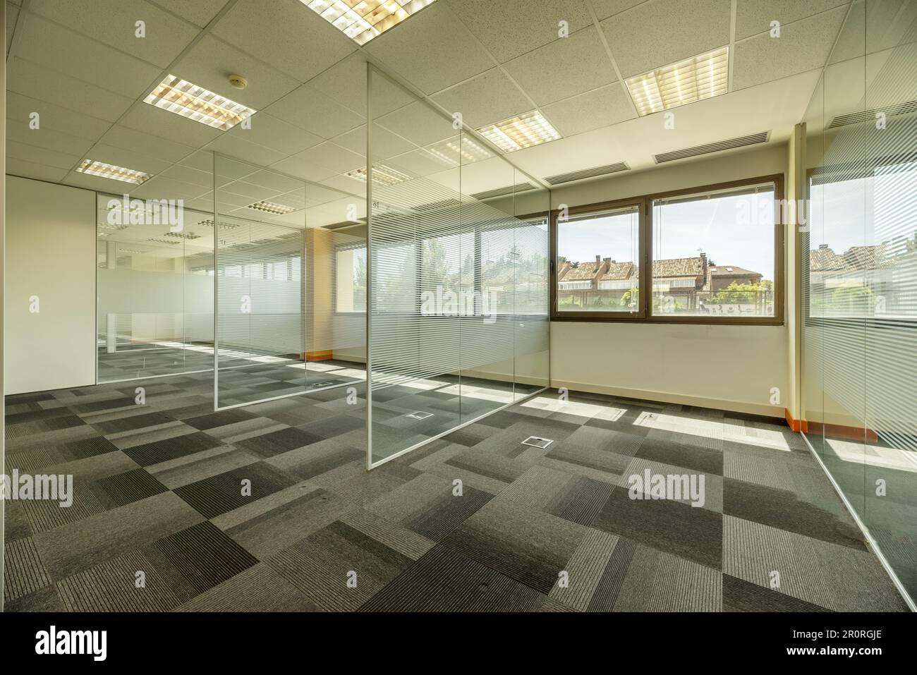 Empty offices with several glass partitions separating cubicles, long ...