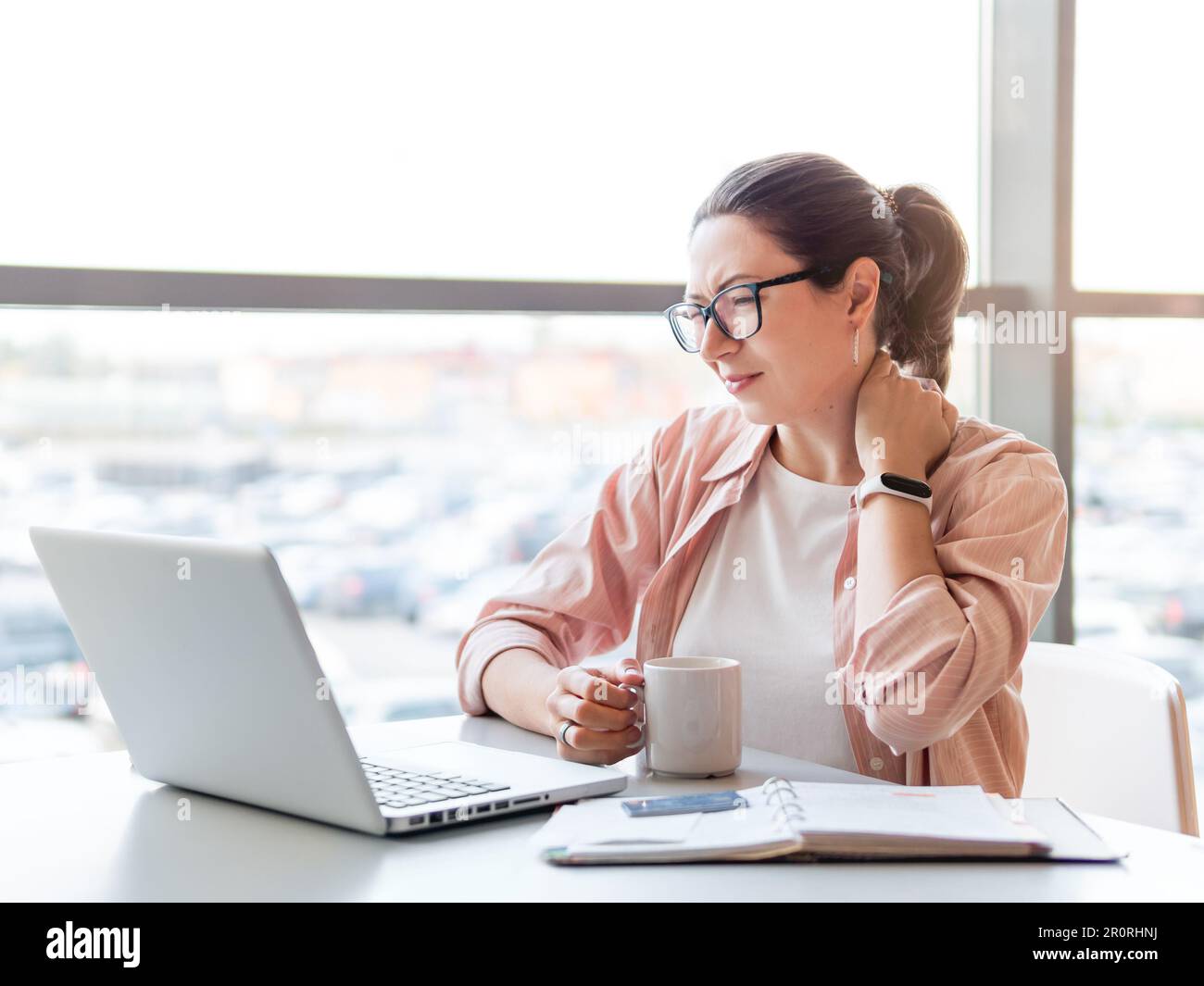Woman winces from pain in her neck. Female office employee tries to ...