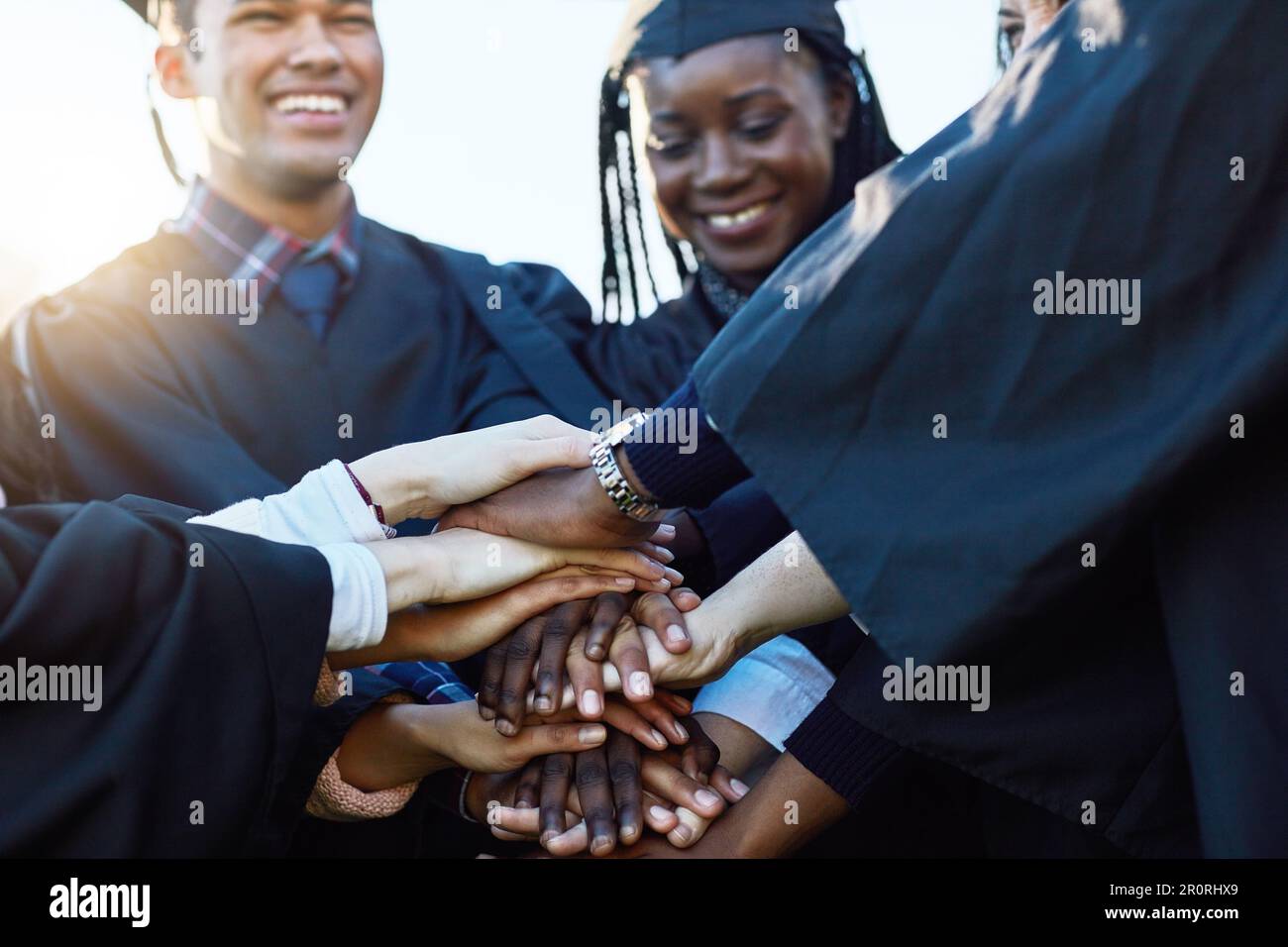 Heres to our future. a group of students joining their hands together ...