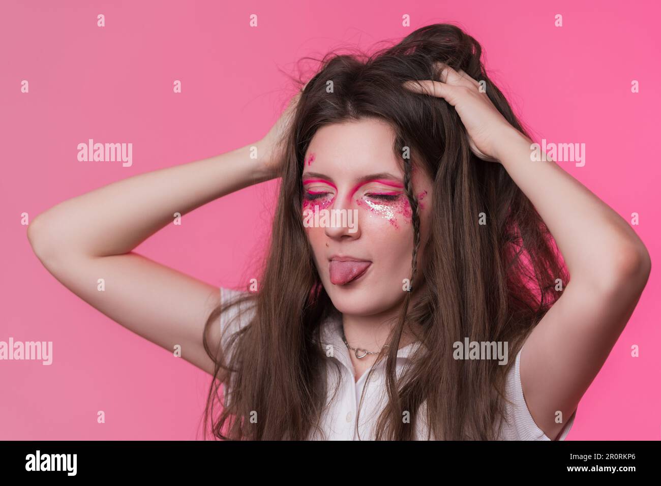 Portrait of playful young adult woman with eyes closed, tongue sticking ...