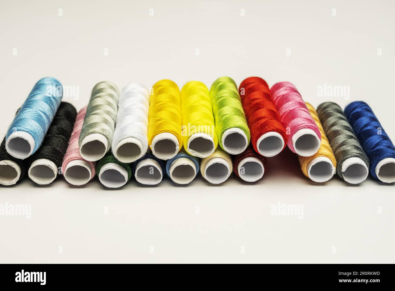 A bunch of spools of different colored sewing thread on a white surface ...