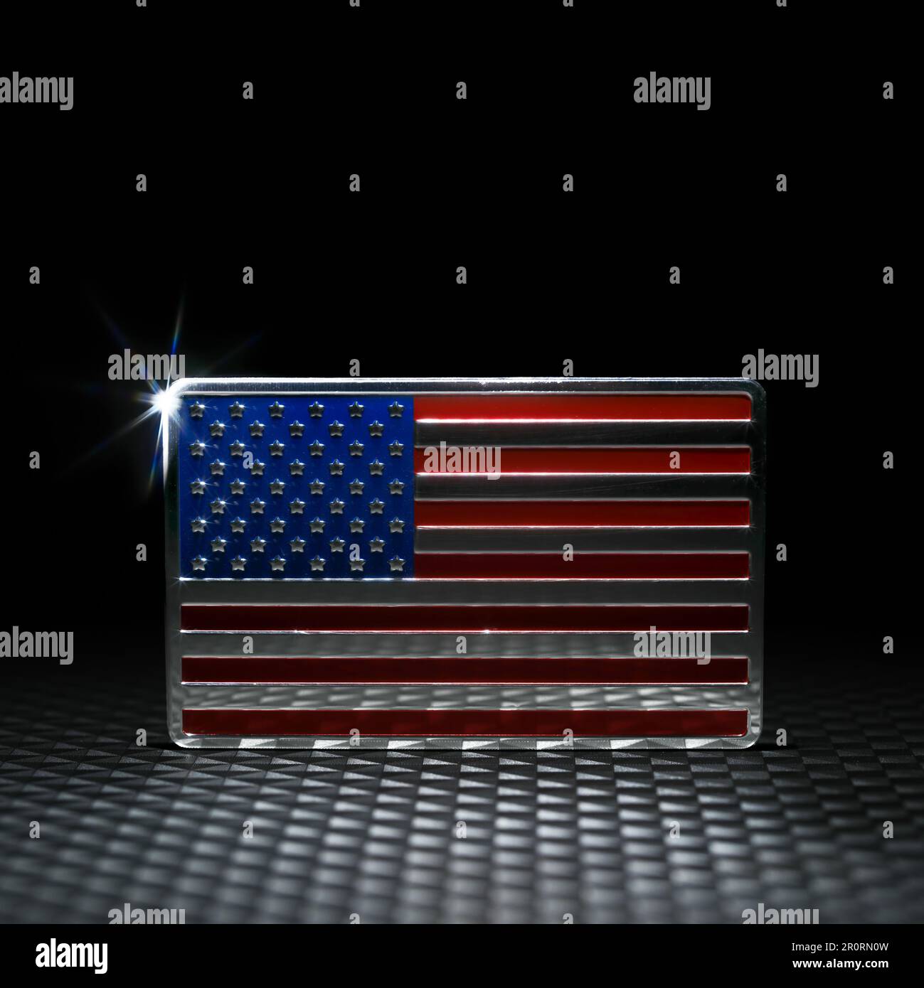 Spotlight on shiny US American flag emblem on dark carbon fiber ...