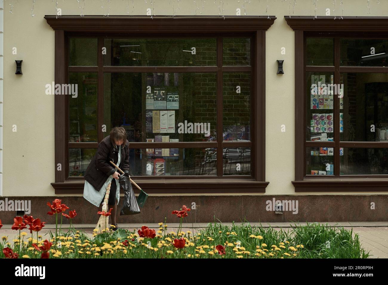 A woman sweeps next to the windows of a pharmacy on the Victory Day of ...