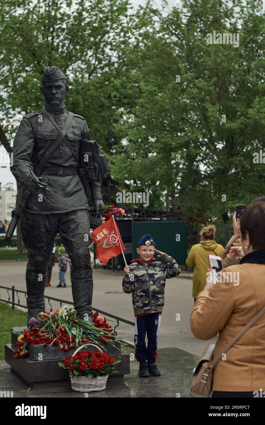 A boy holds a flag and wears a military cap is photographed near the ...