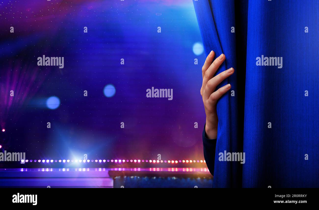 Hand are opening the curtain of a stage. the show is about to begin ...