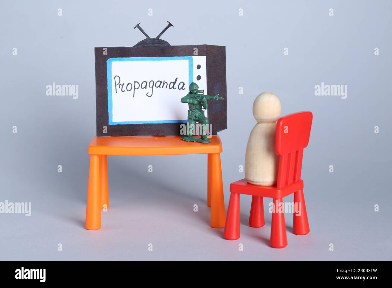 Hybrid warfare concept. Human figure watching TV propaganda at gunpoint ...
