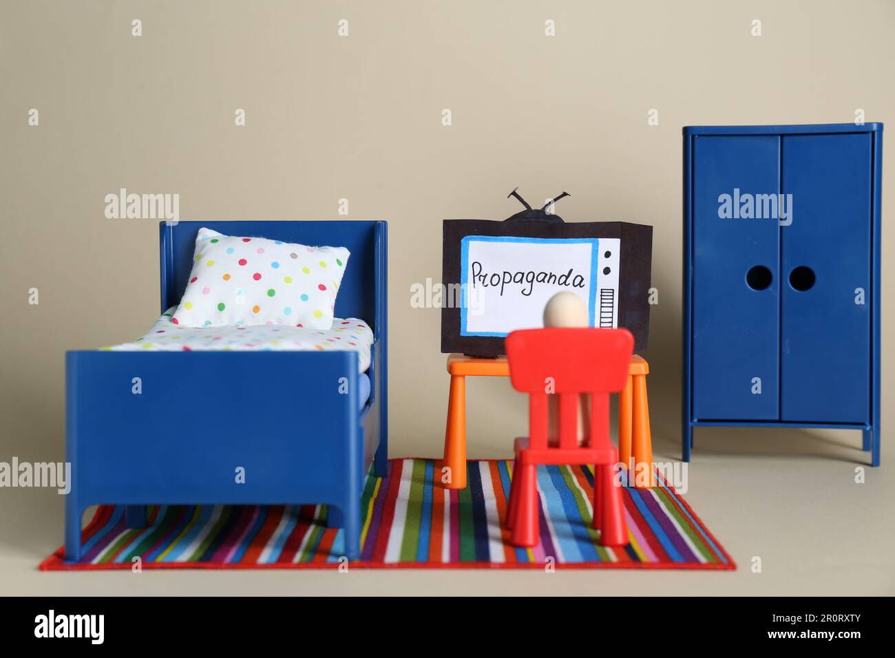 Propaganda concept. Wooden figure in front of paper TV in toy room ...
