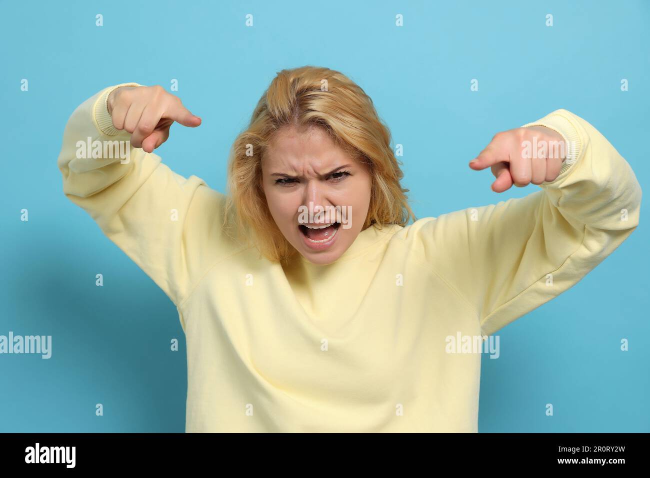 Aggressive young woman pointing on light blue background Stock Photo ...
