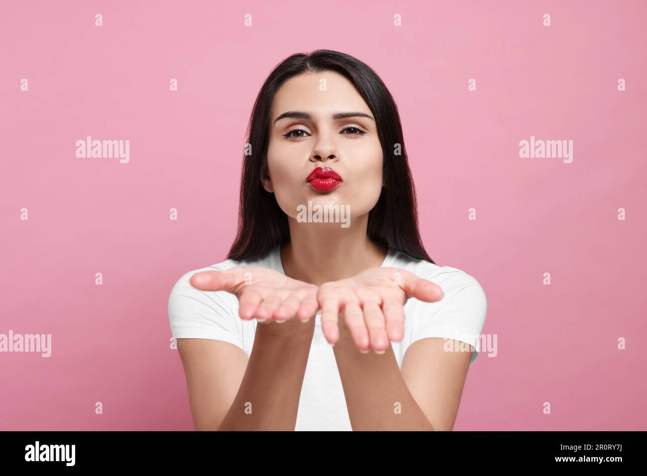 Beautiful young woman blowing kiss on pink background Stock Photo - Alamy
