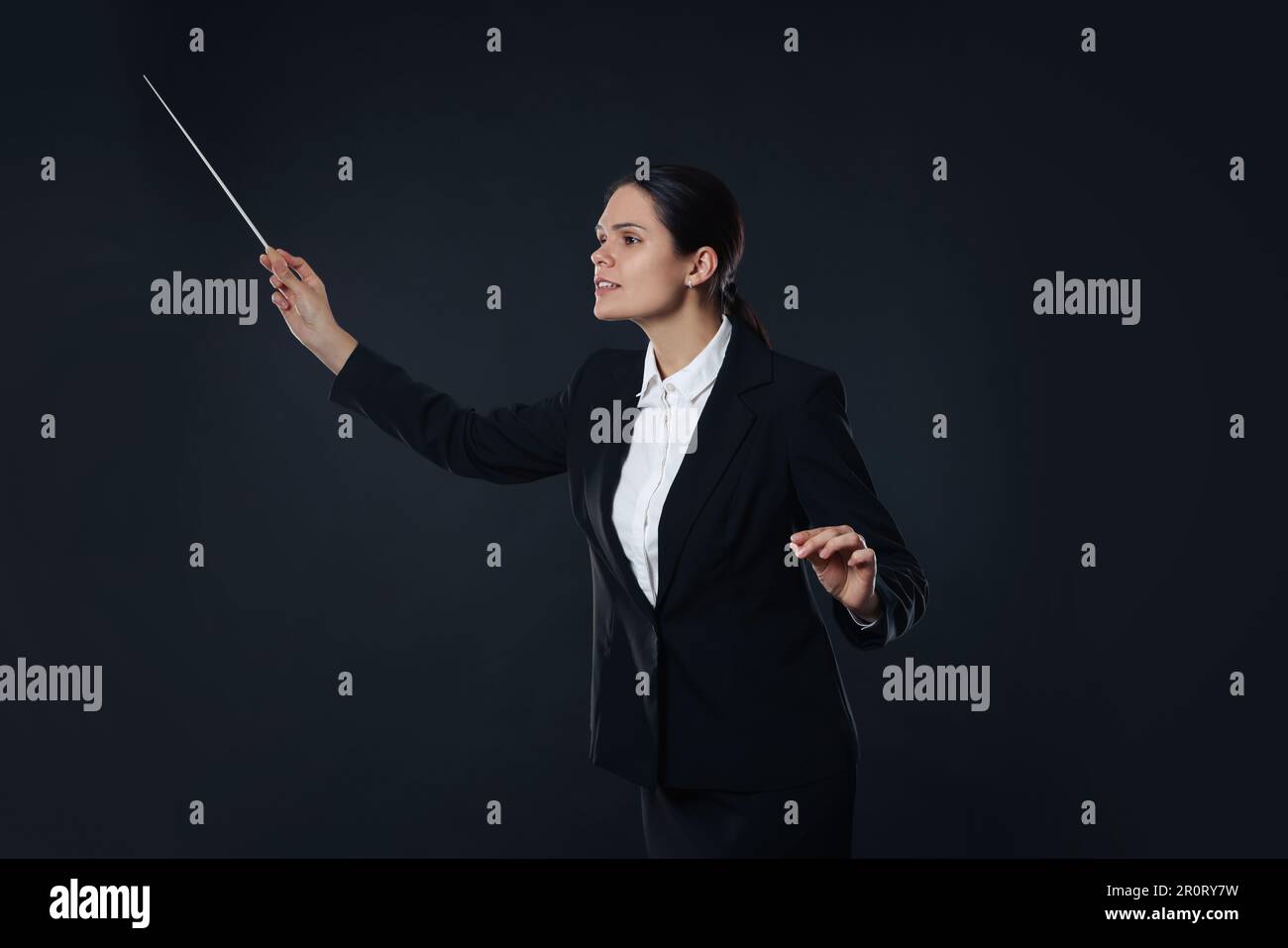 Professional conductor with baton on dark background Stock Photo - Alamy