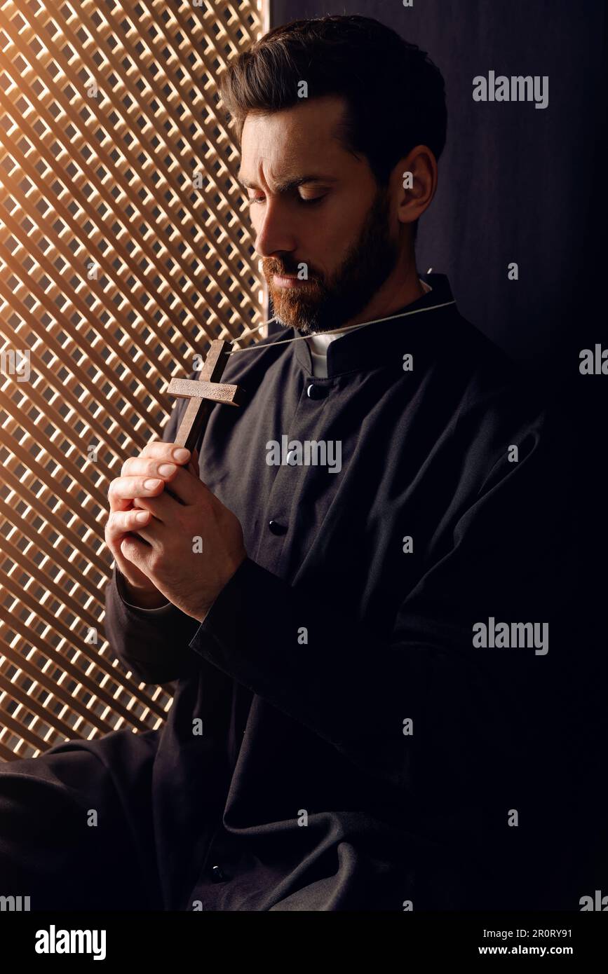 Catholic priest in cassock holding cross in confessional booth Stock ...