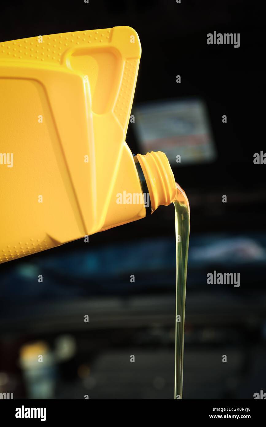 Pouring motor oil from yellow container on blurred background, closeup ...