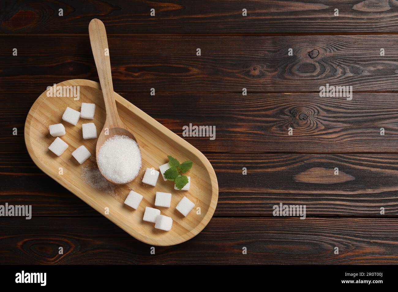 Tray and spoon with white sugar on wooden table, top view. Space for ...