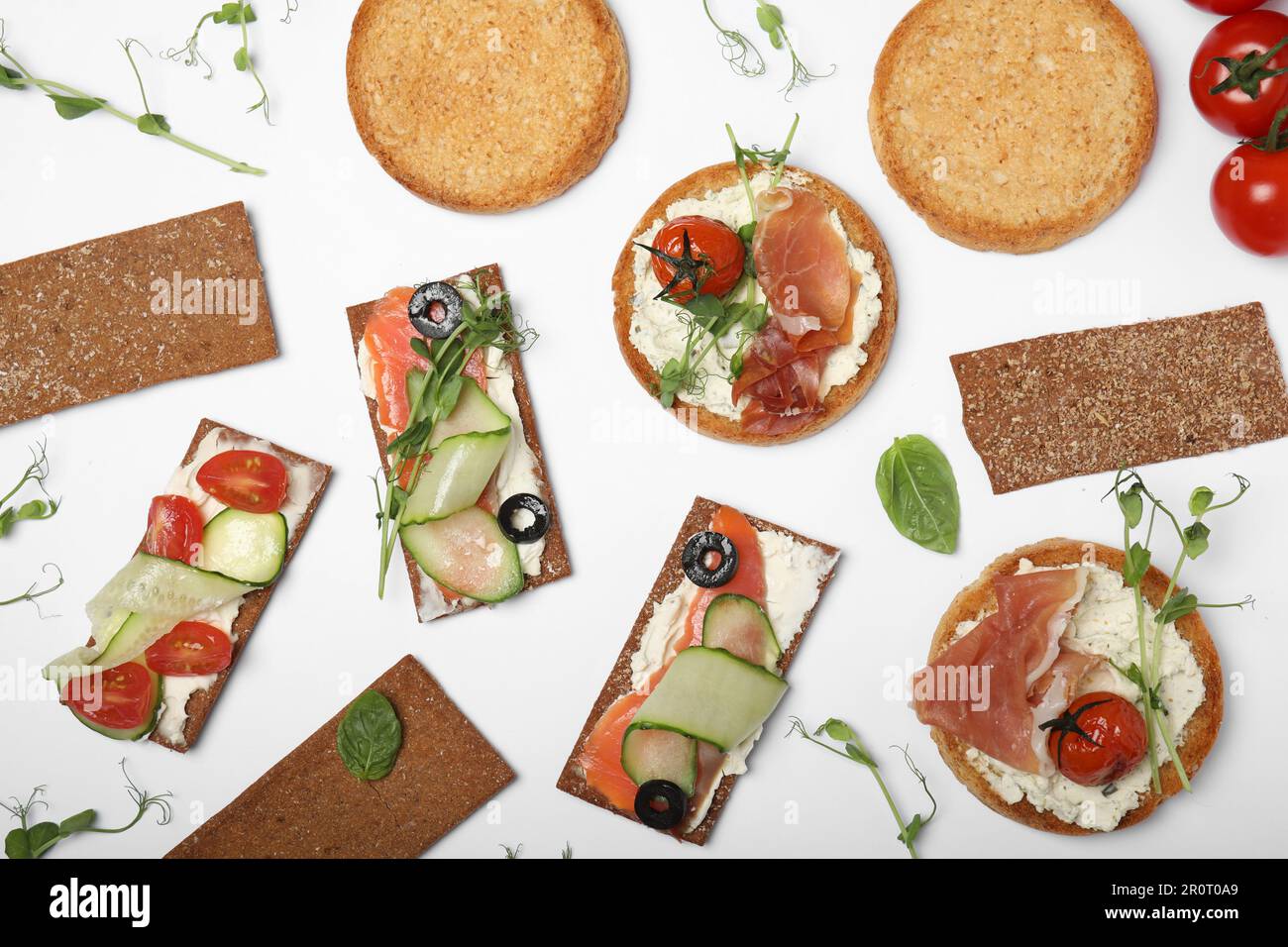 Tasty rusks and rye crispbreads with different toppings on white ...