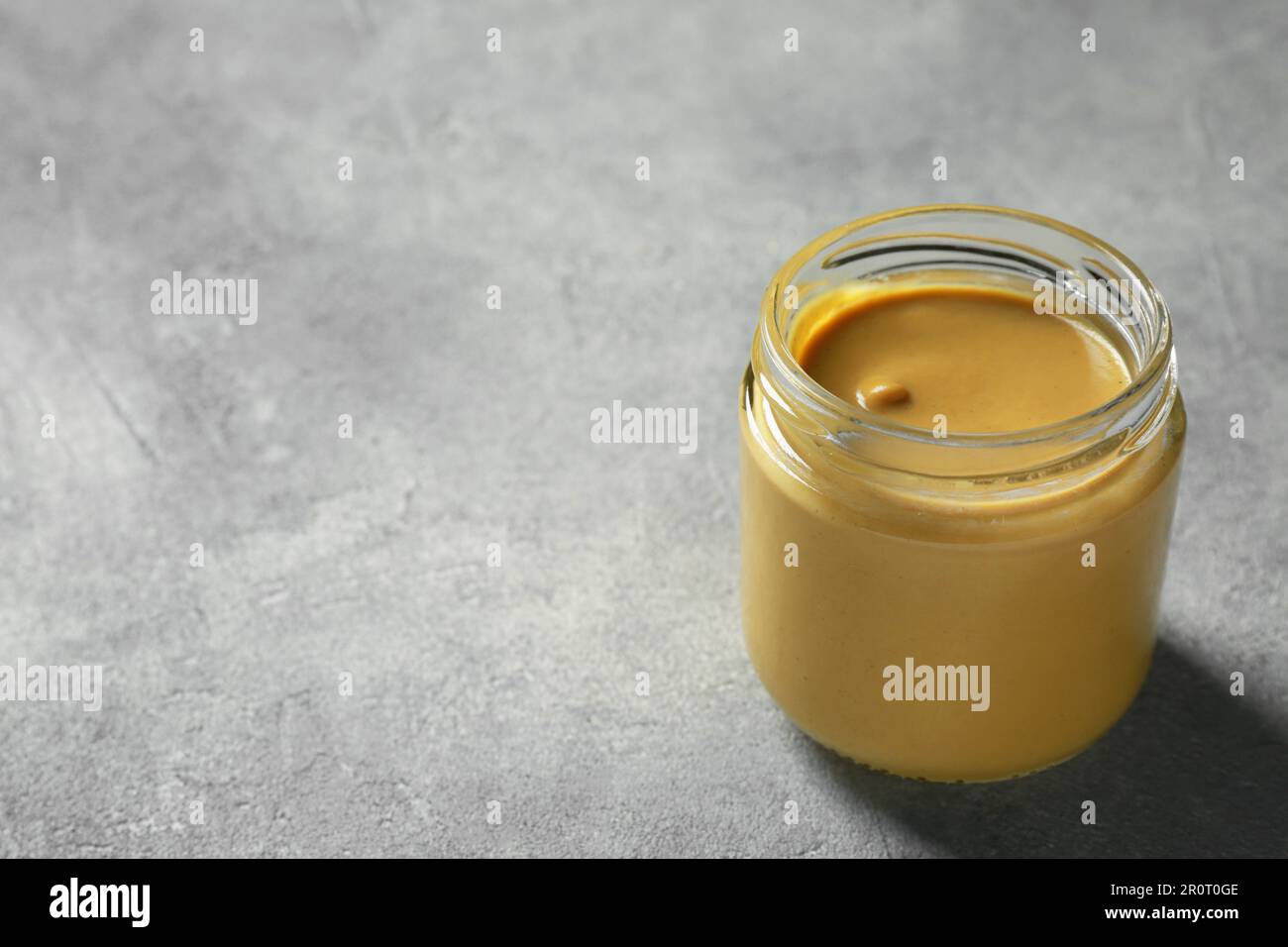 Spicy mustard in glass jar on grey table. Space for text Stock Photo ...