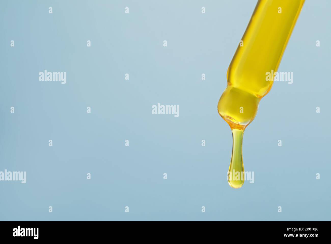 Dripping yellow serum from pipette on grey background, closeup. Space ...
