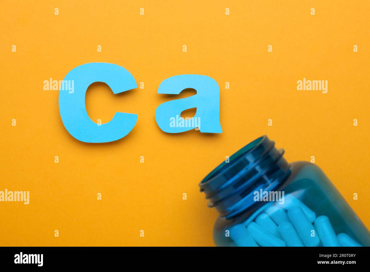 Open bottle and calcium symbol made of light blue letters on orange ...