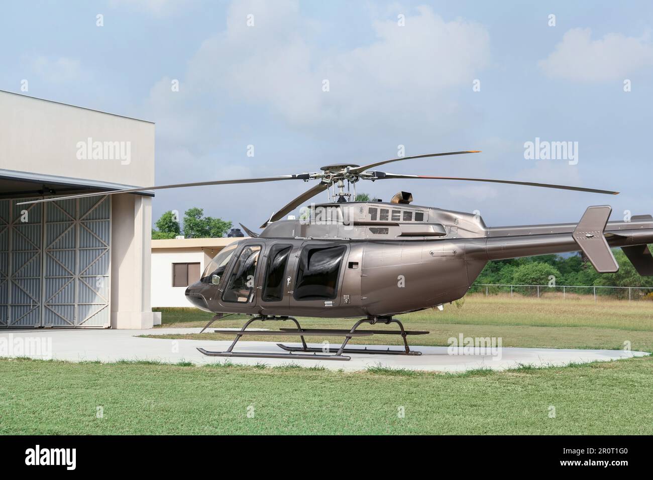 Beautiful helicopter on helipad in field near hangar Stock Photo - Alamy