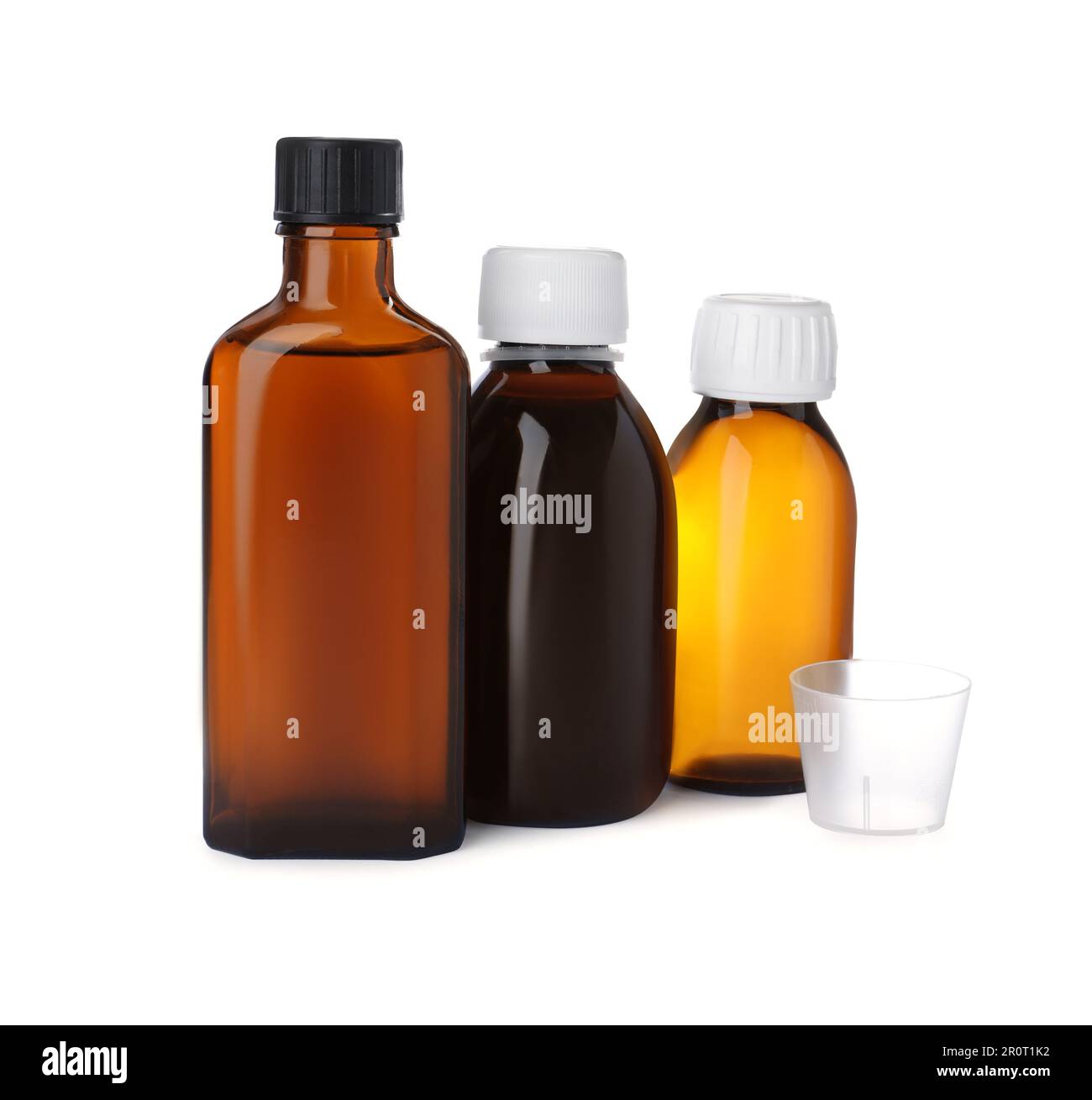Bottles of syrups with measuring cup on white background. Cough and ...
