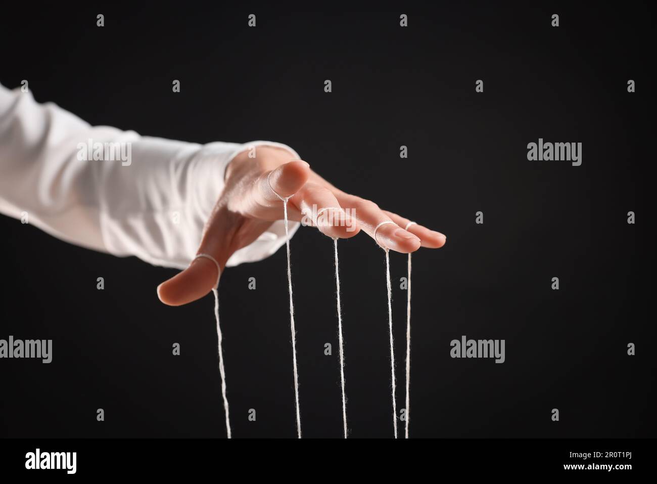 Woman pulling strings of puppet on black background, closeup Stock ...
