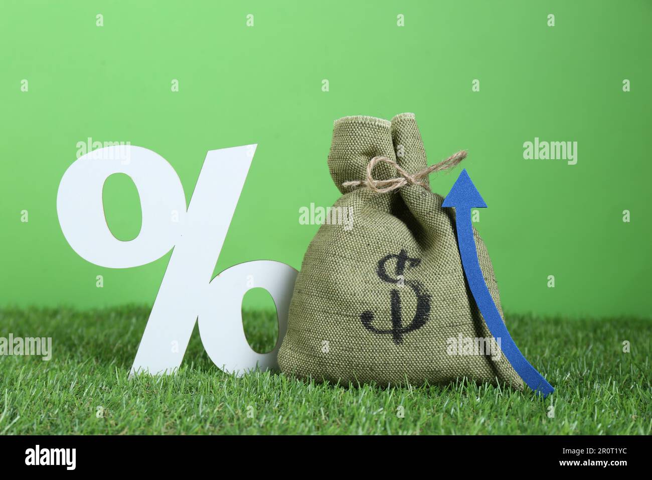 Bag with money, up arrow and percent symbol against green background ...