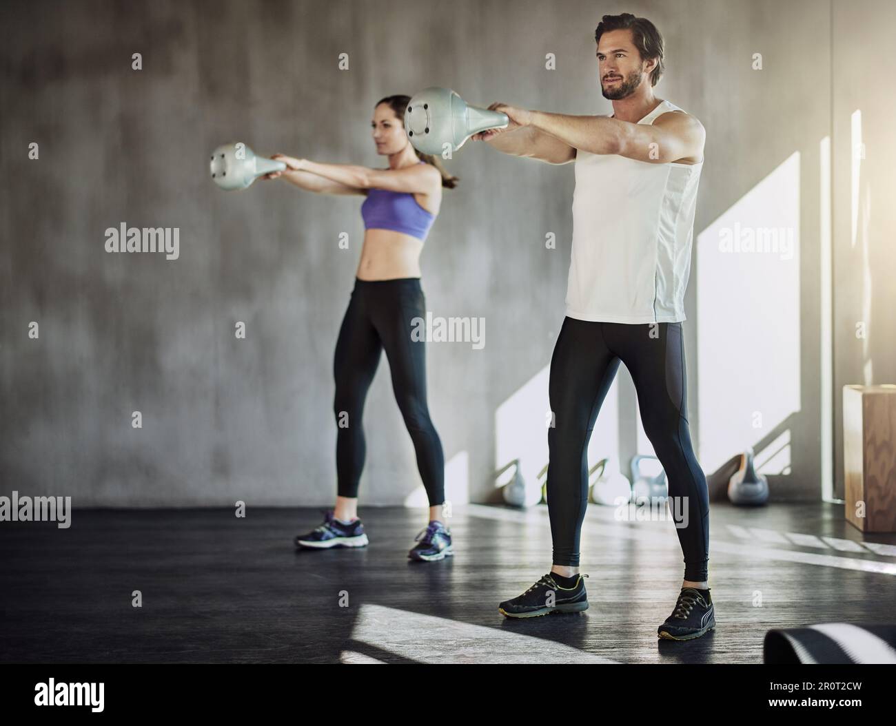 Getting a full body workout. two young people working out in the gym ...