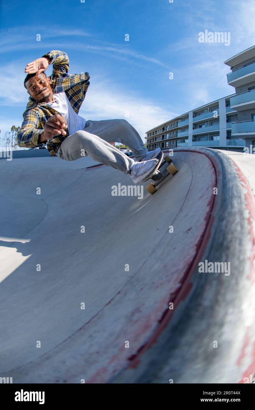 Surf skater performing a high speed turn on a skatepark during a sunny ...